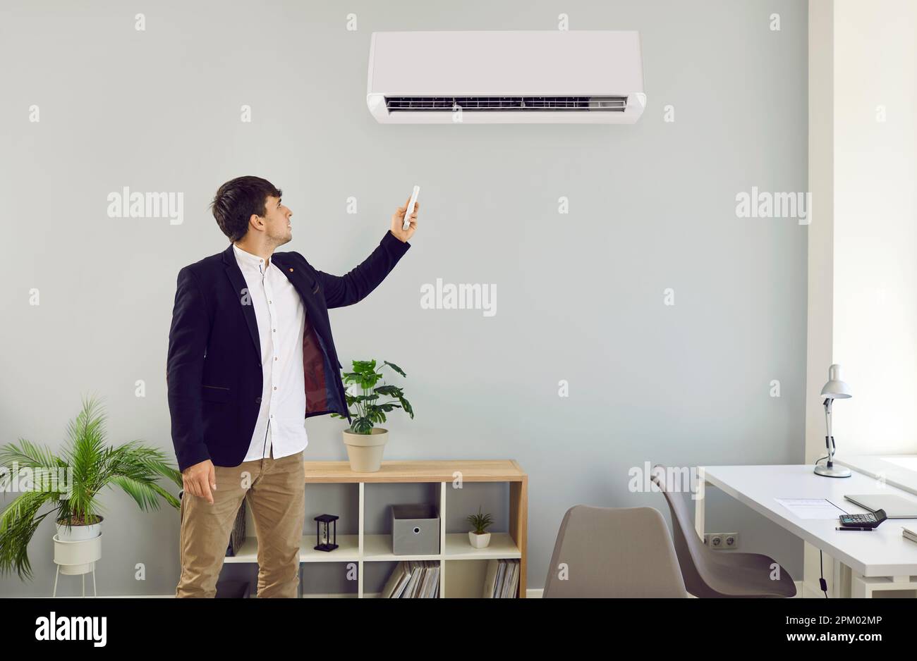 Young businessman switches on a modern air conditioner in the office ...
