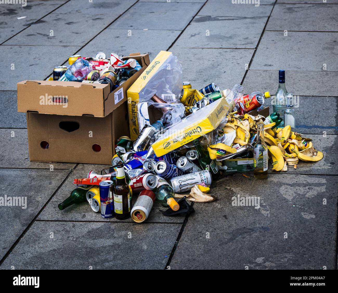 A diverse array of beer bottles and boxes scattered on a concrete ...