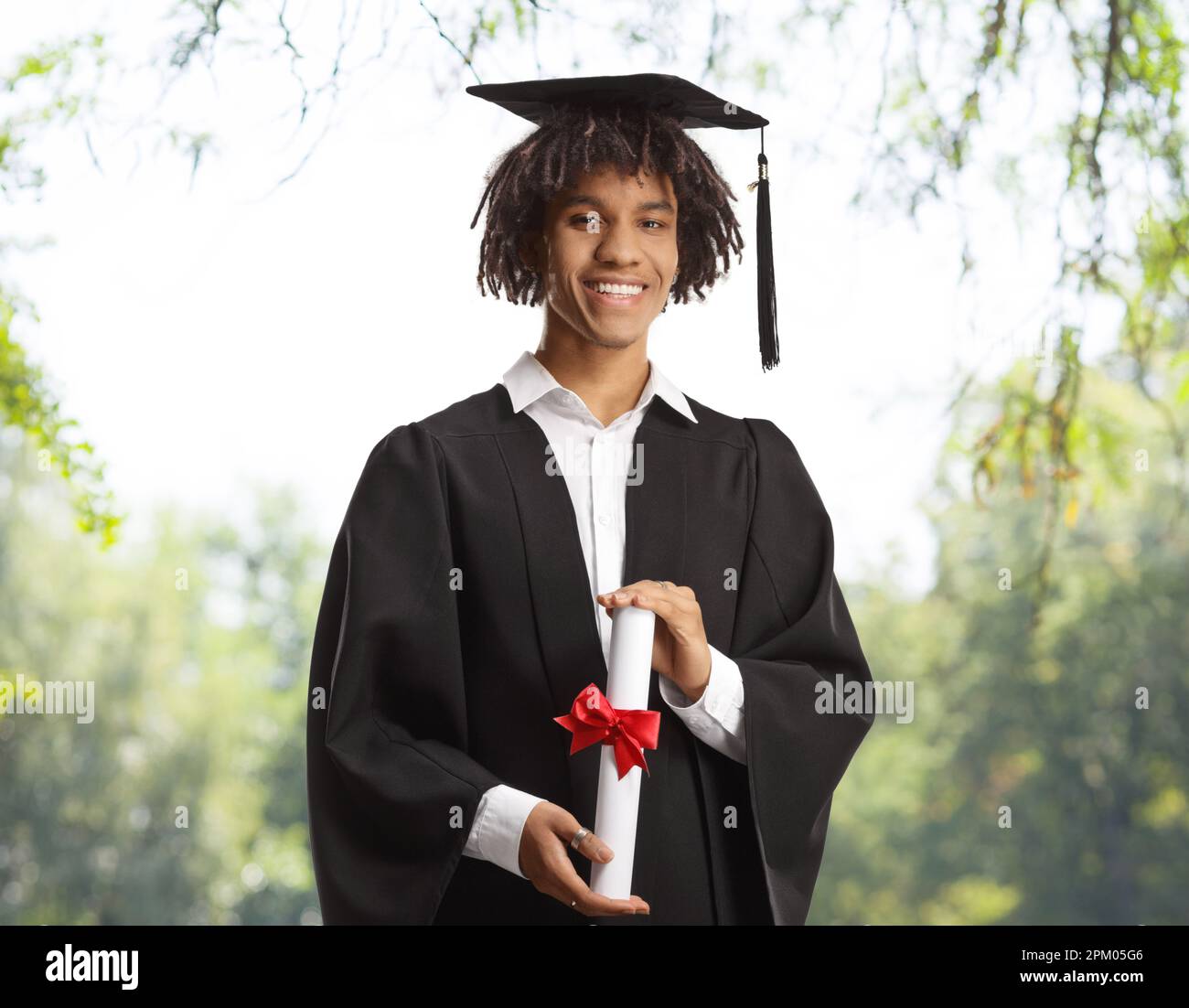 African american male student wearing a graduation gown and holding a ...