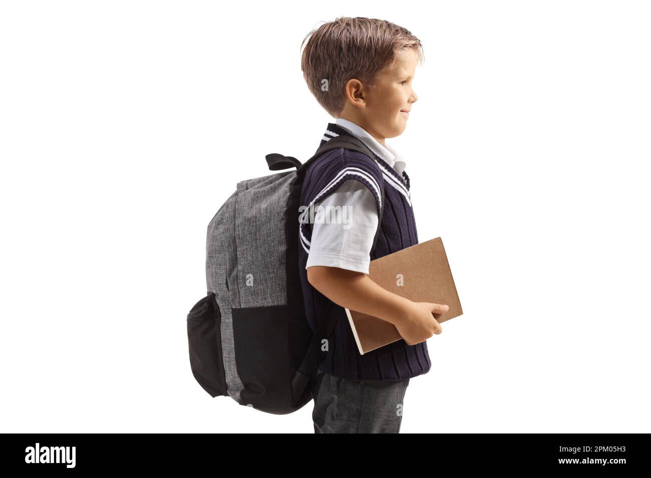 Profile shot of a schoolboy in a uniform standing and holding a book ...