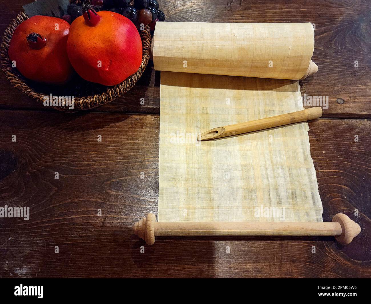 Bamboo reed pen on a blank ancient papyrus scroll with pomegranate ...
