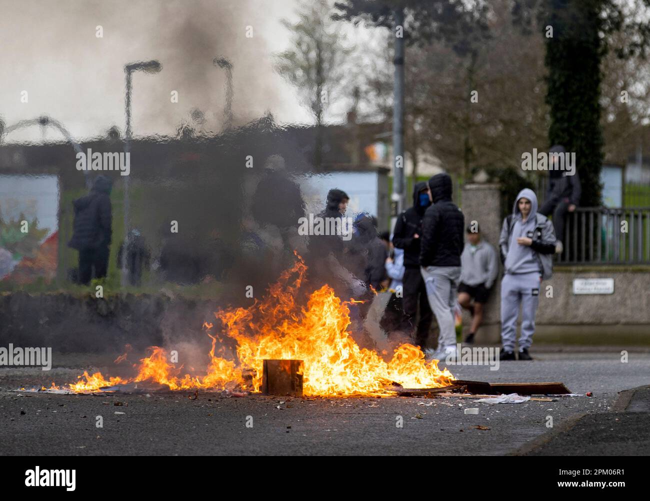 Youths stand beside a barricade on fire in the Creggan area of ...