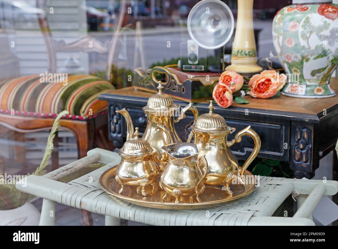 Antique store showing antiques such as a silver tea set. Seen through ...