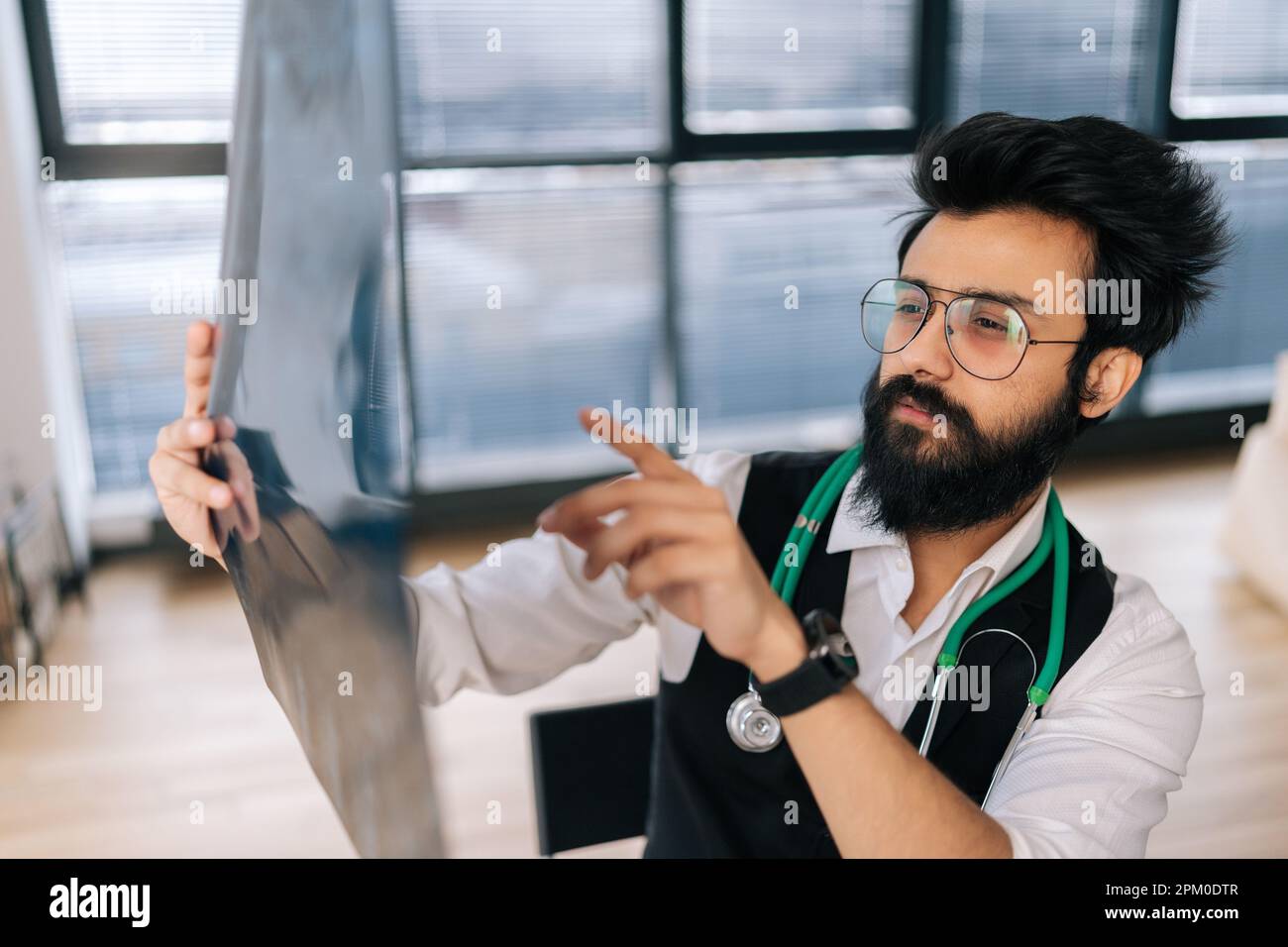 Close-up of pensive Indian male doctor in glasses thinking on diagnosis ...