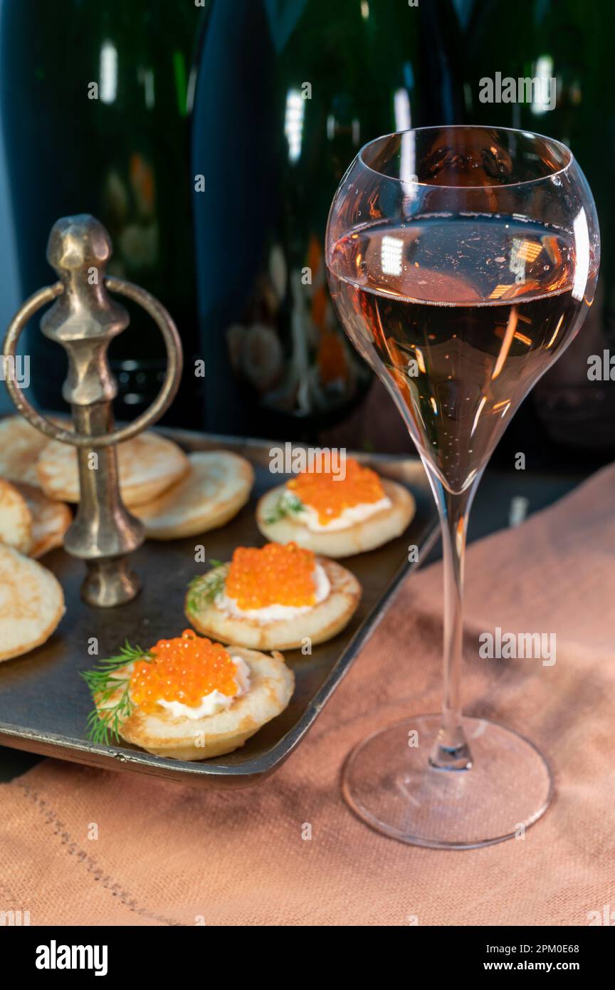 Tasting of rose Champagne sparkling wine with red caviar in cellars of ...