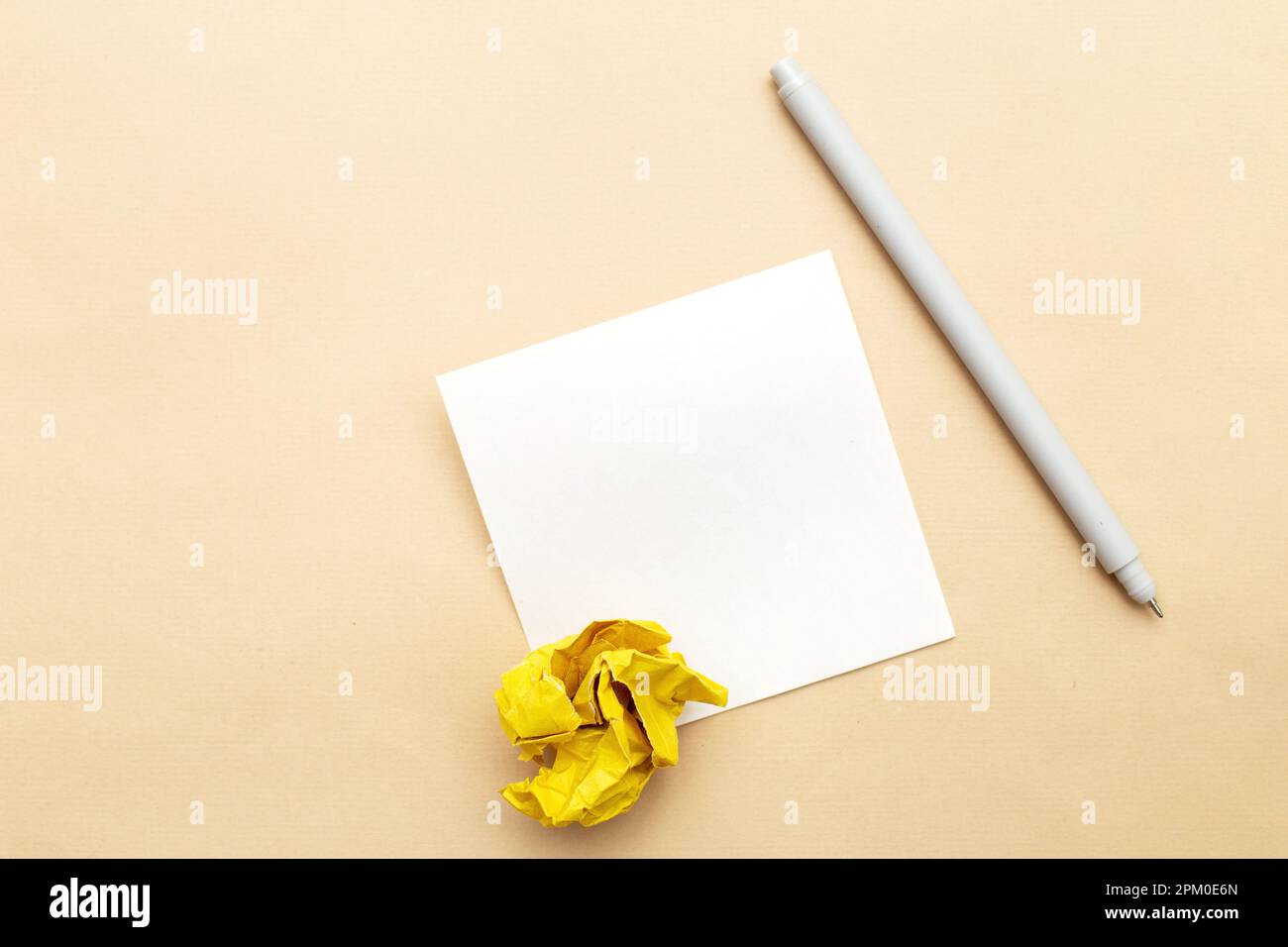 crumpled yelllow paper with a pen and note for writing on beige ...