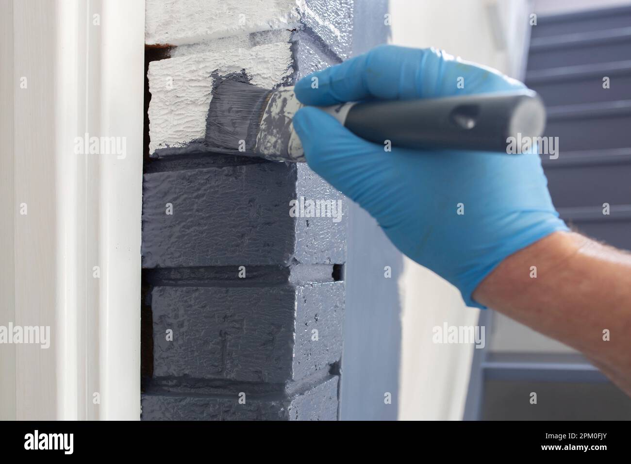 Man painting interior bricks with blue paint using a brush. Do it ...