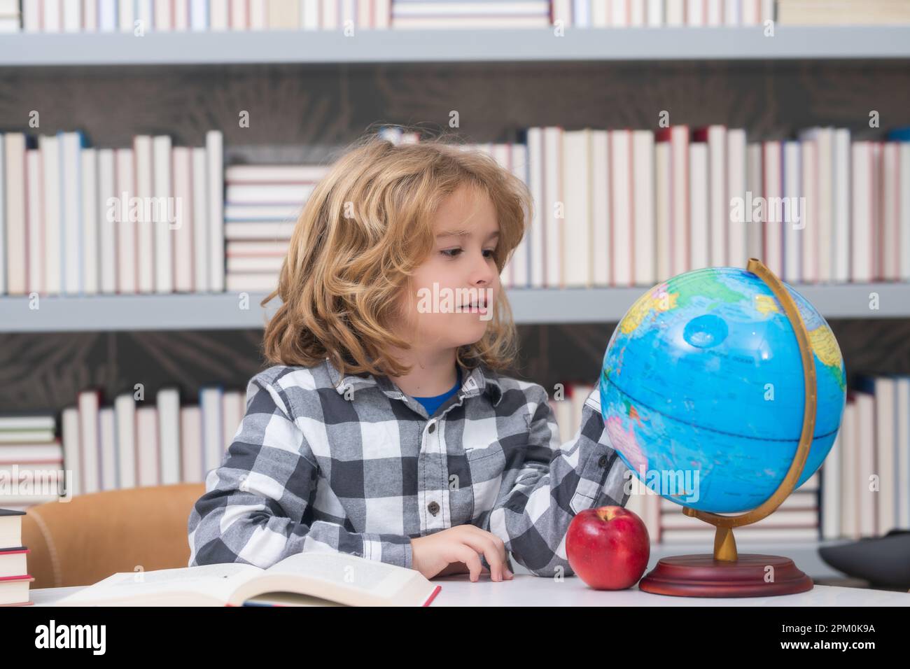School pupil looking at globe in library, geography lesson. School and ...