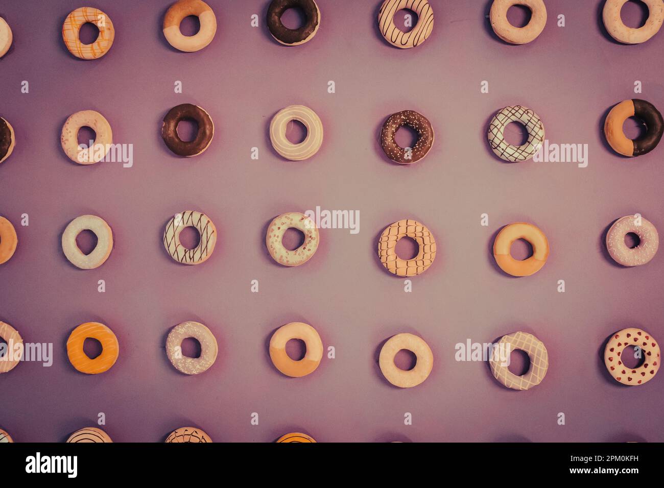 Round donuts food with different decoration on a solid purple pink ...