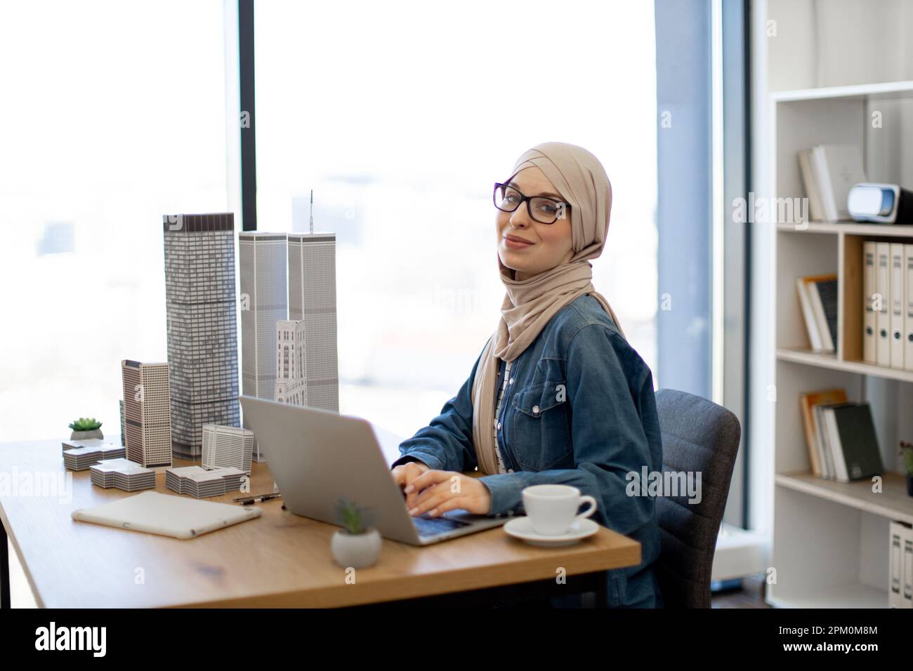 Muslim female architect in hijab working on portable computer at office ...