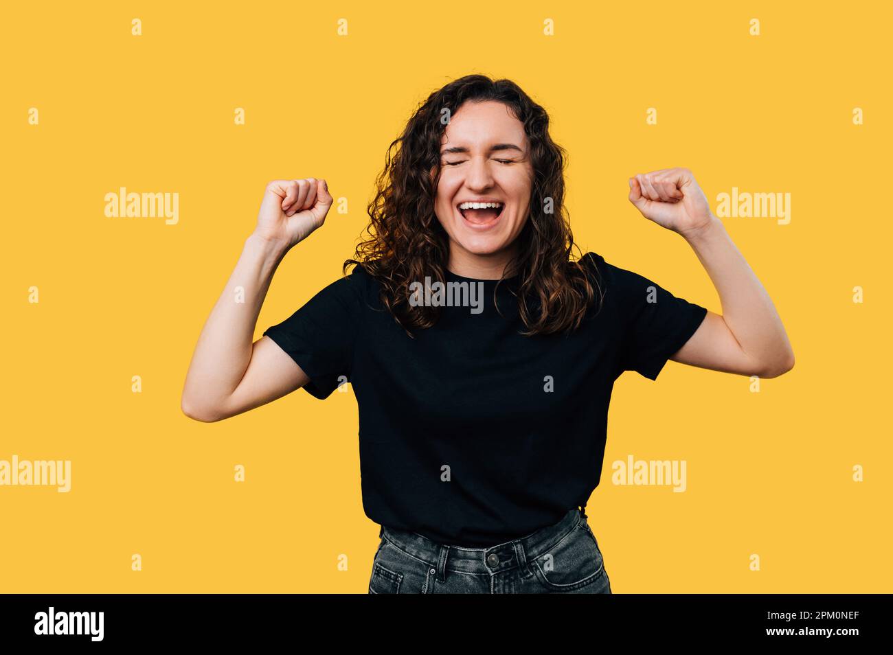 Cheerful woman is making the winner gesture while screaming with eyes ...