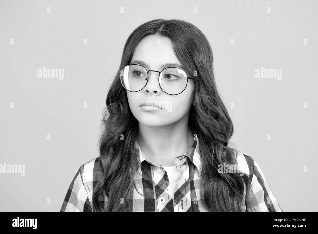 Portrait of beautiful serious teenage girl on yellow studio background ...