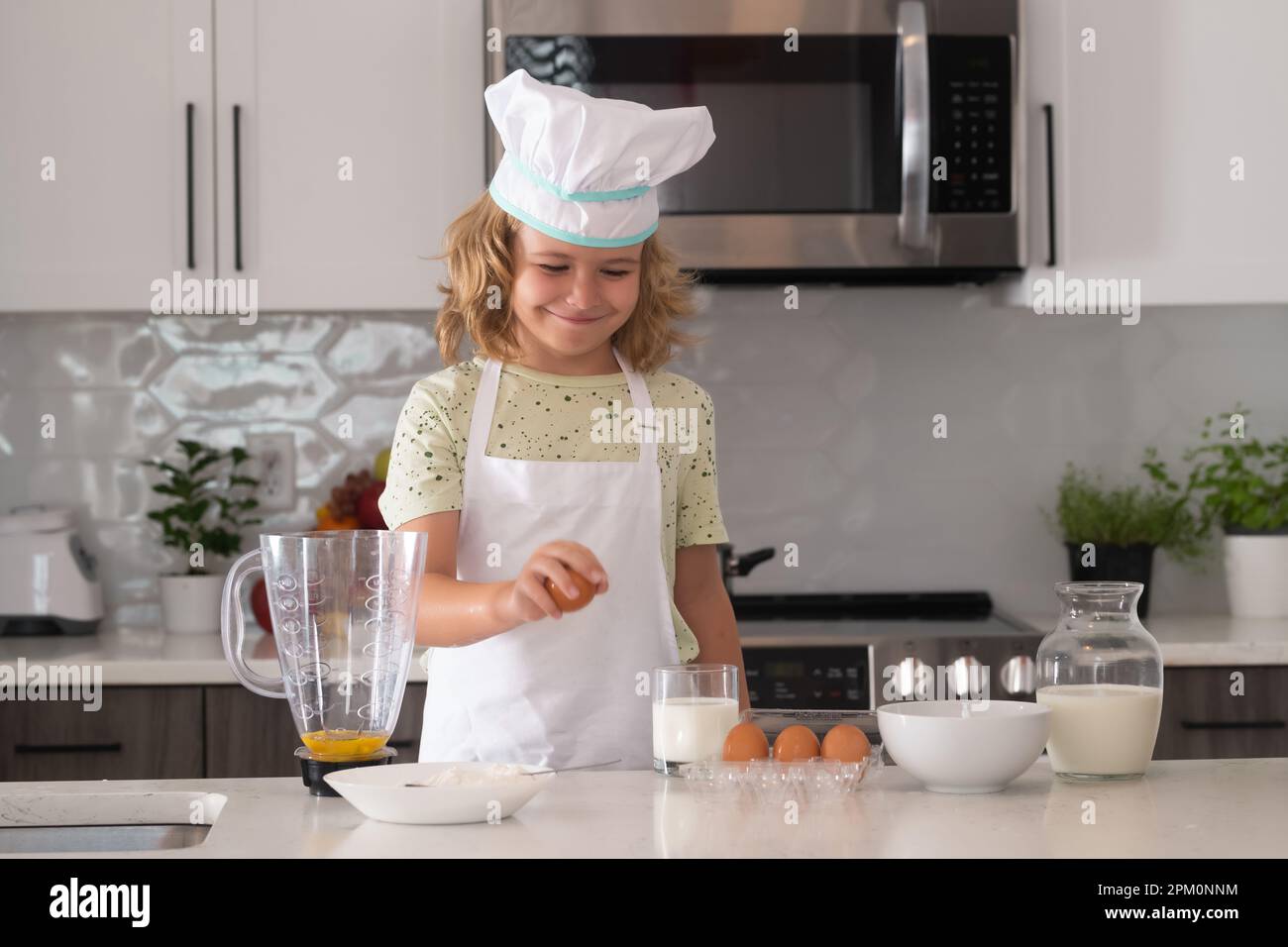 Chef kid boy baking on the kitchen. Child chef cook prepares food at ...