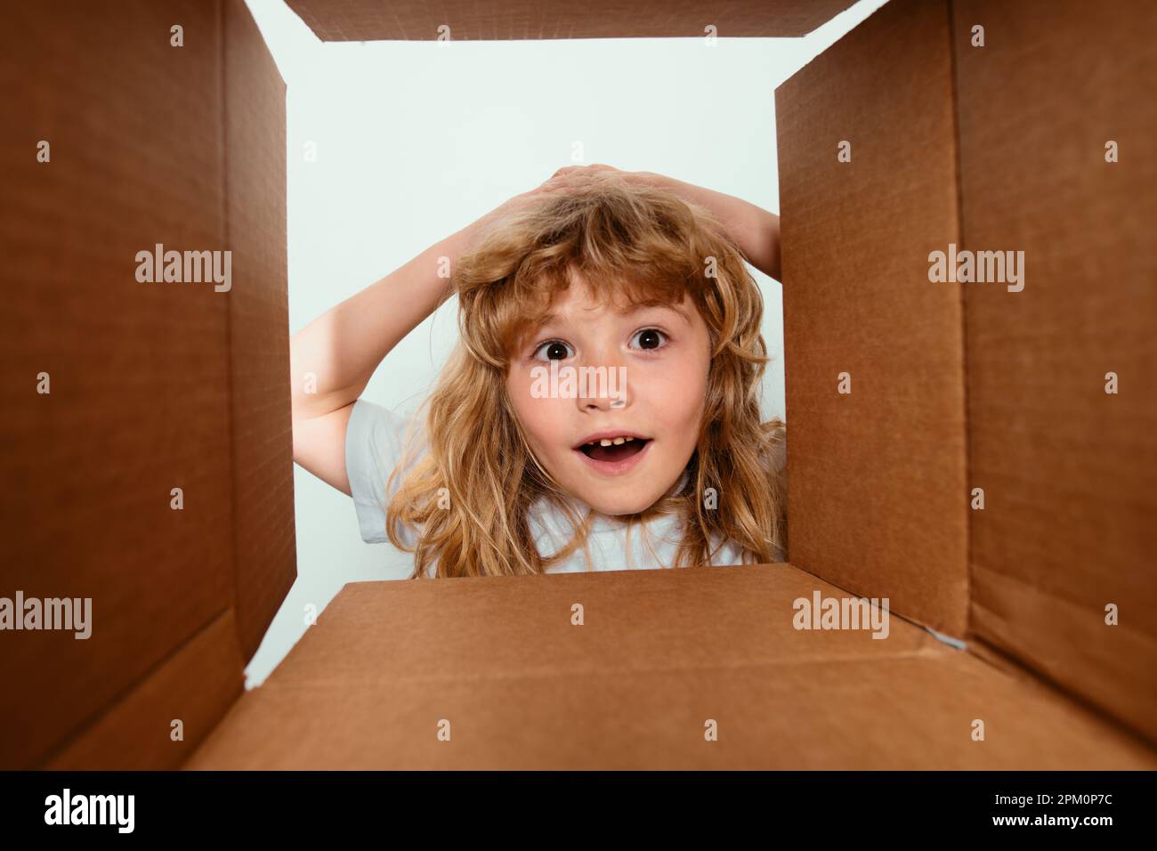 Funny surprised shocked child boy is opening gift and looking inside ...