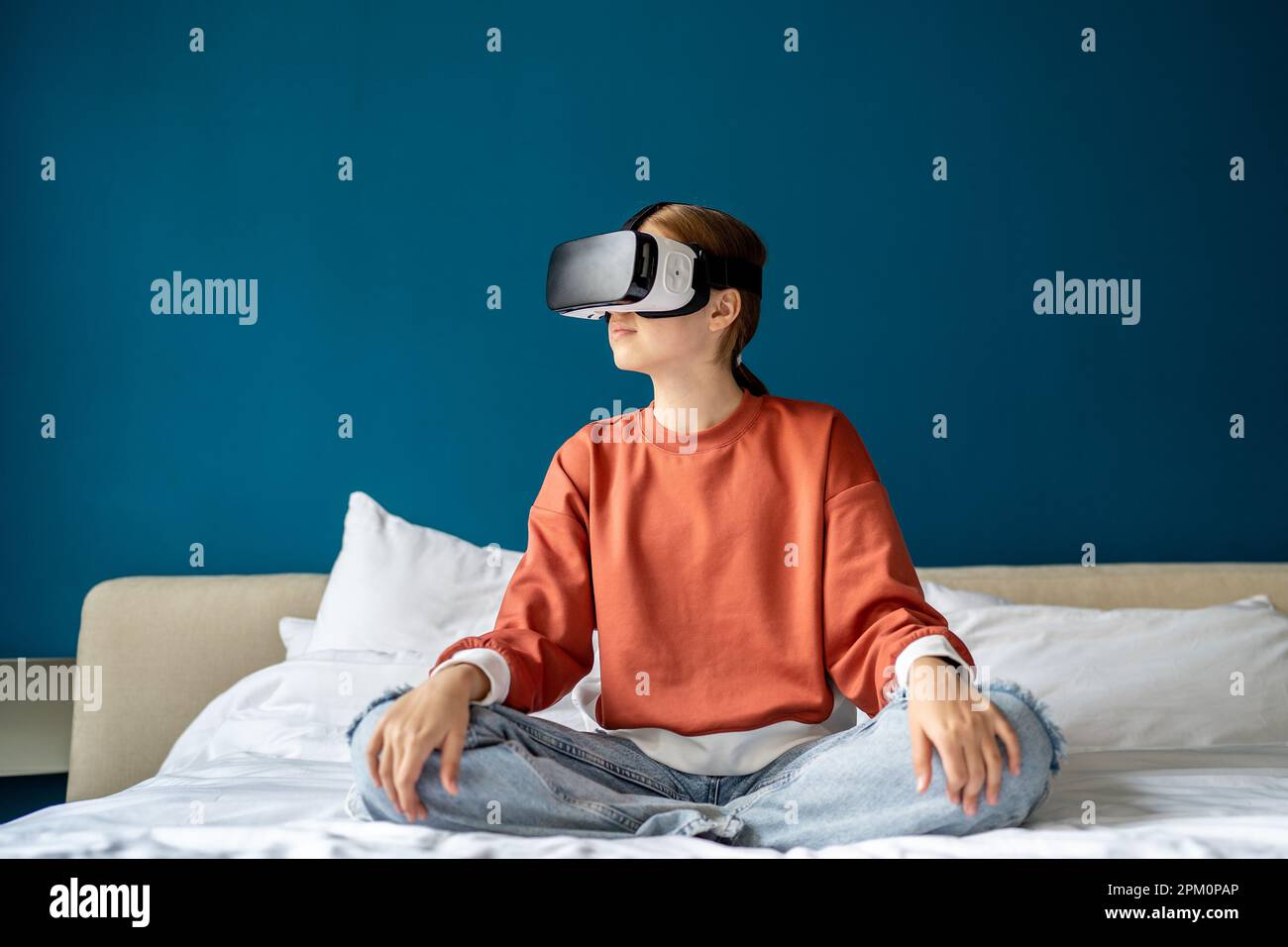 Teenage girl child sitting on bed in vr headset watching 360-degree ...