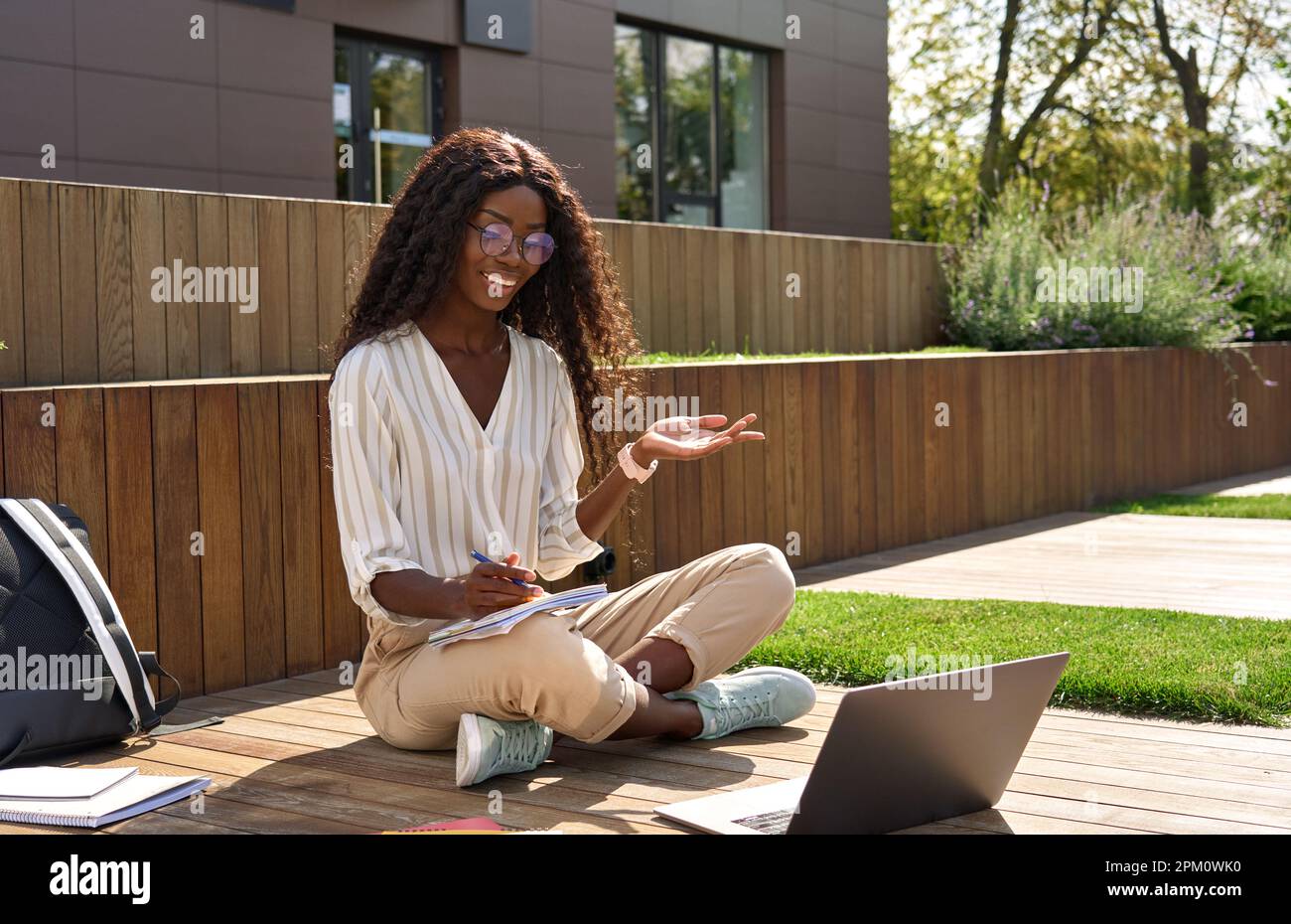 Young happy black woman student learning virtual online class outdoors ...