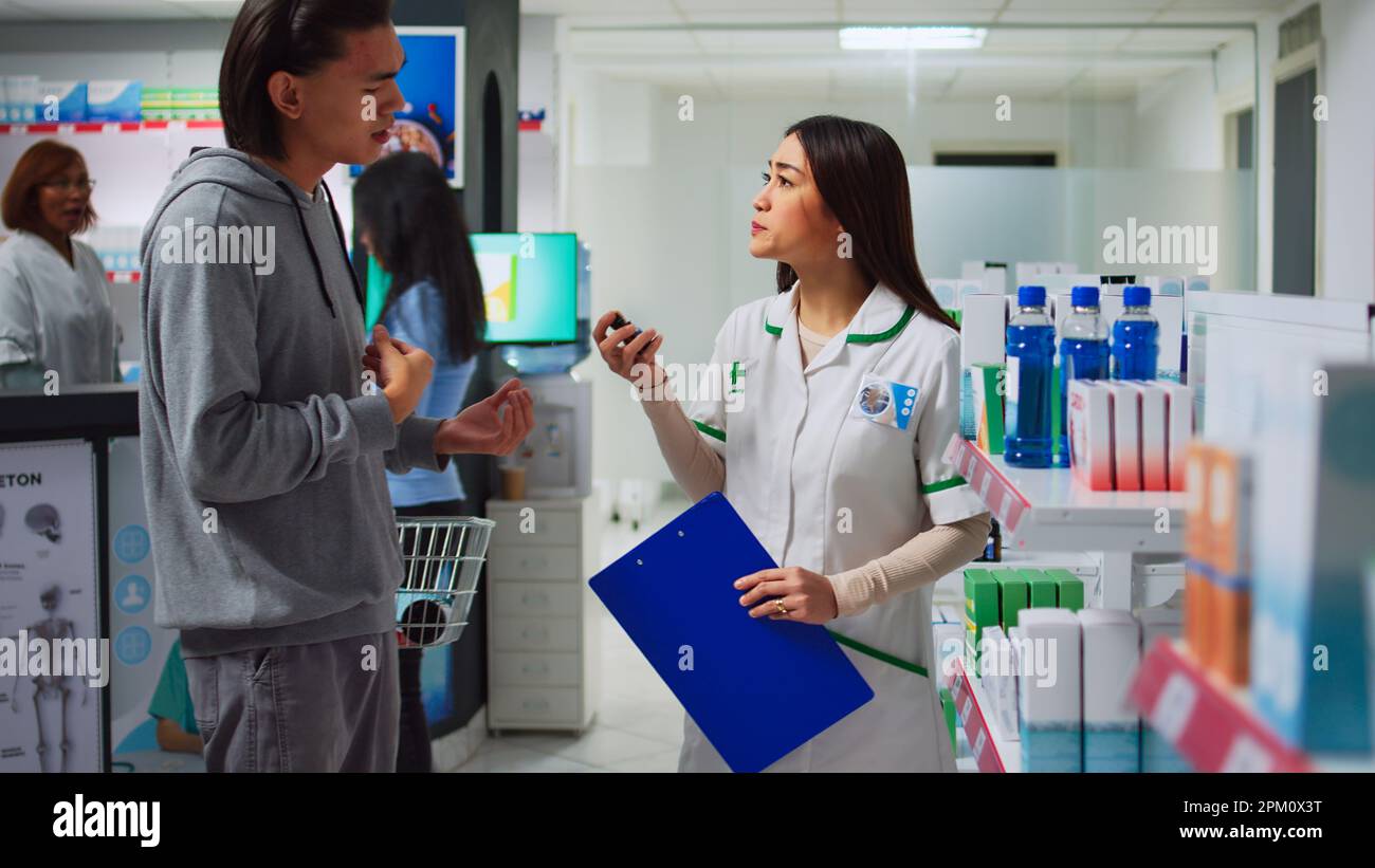 Young man with sore throat asking pharmacist about medicine, dealing ...
