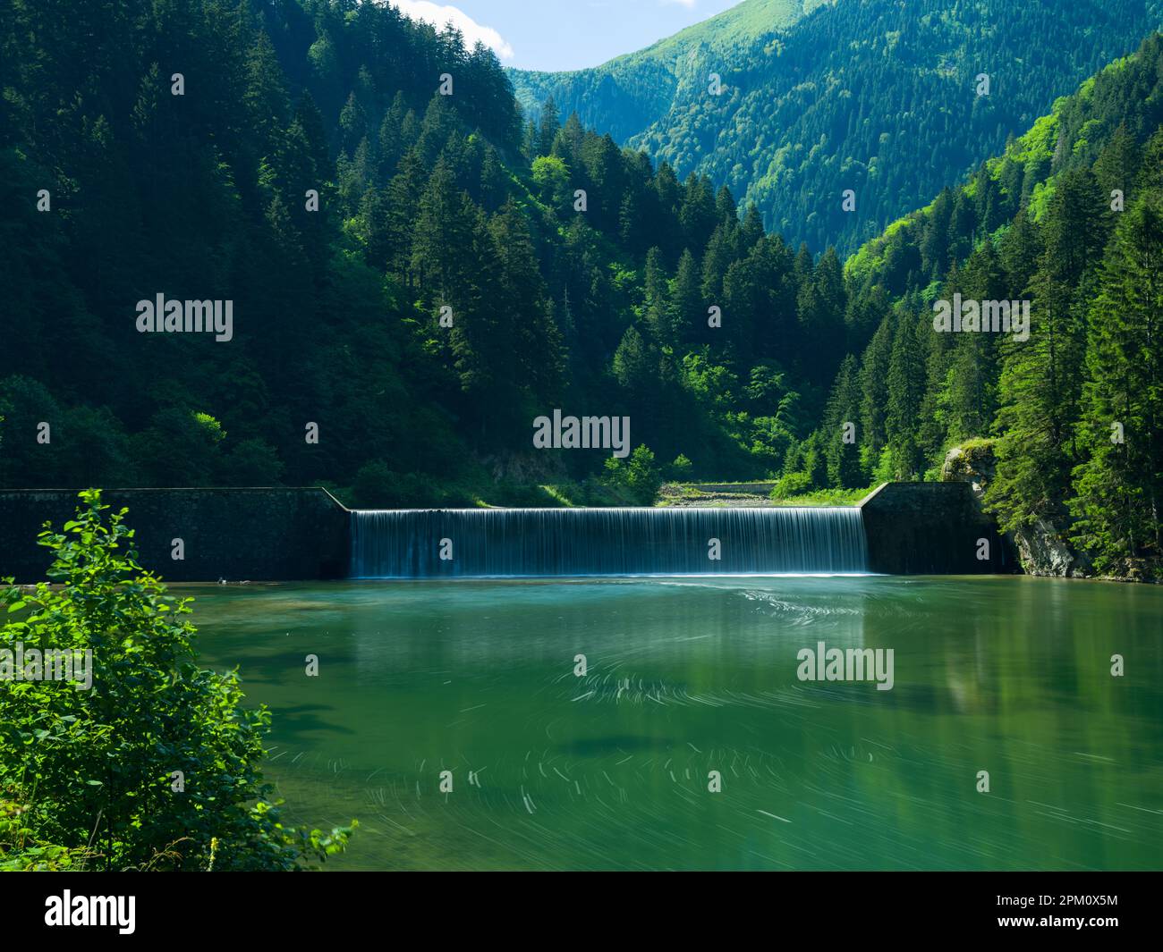 Waterfall flowing into the still lake in spring time. Uzungol waterfall ...