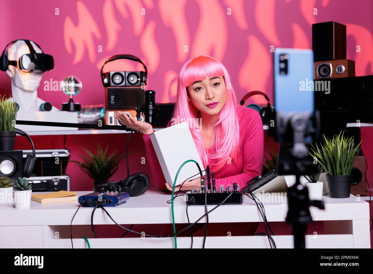 Asian vlogger with pink hair holding white box advertising product in ...