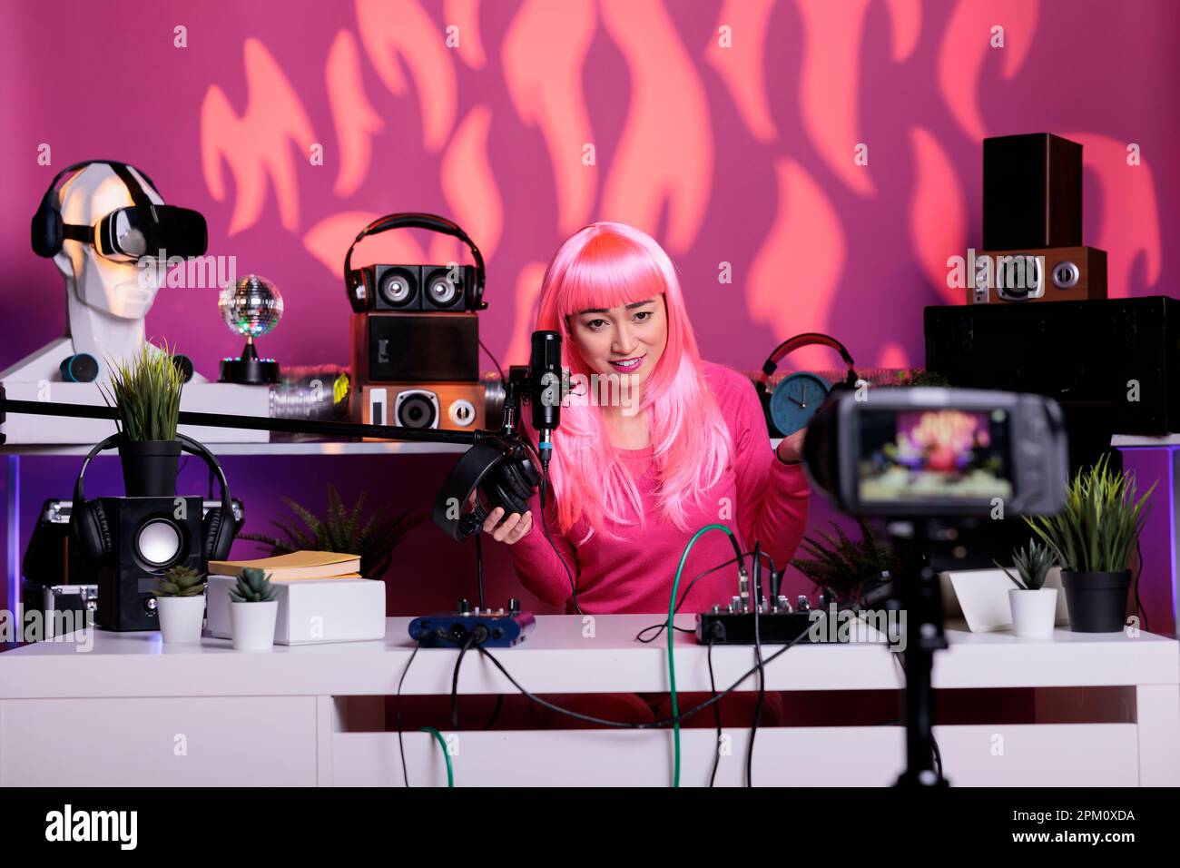 Asian vlogger looking into camera while recording creative podcast in vlogging studio discussing ...