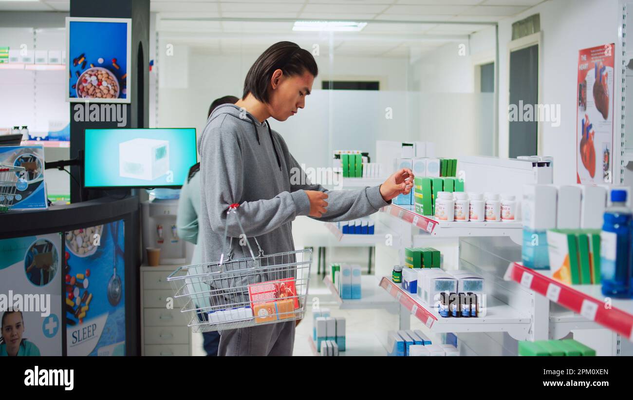 Male customer analyzing supplements boxes on pharmacy shelves ...