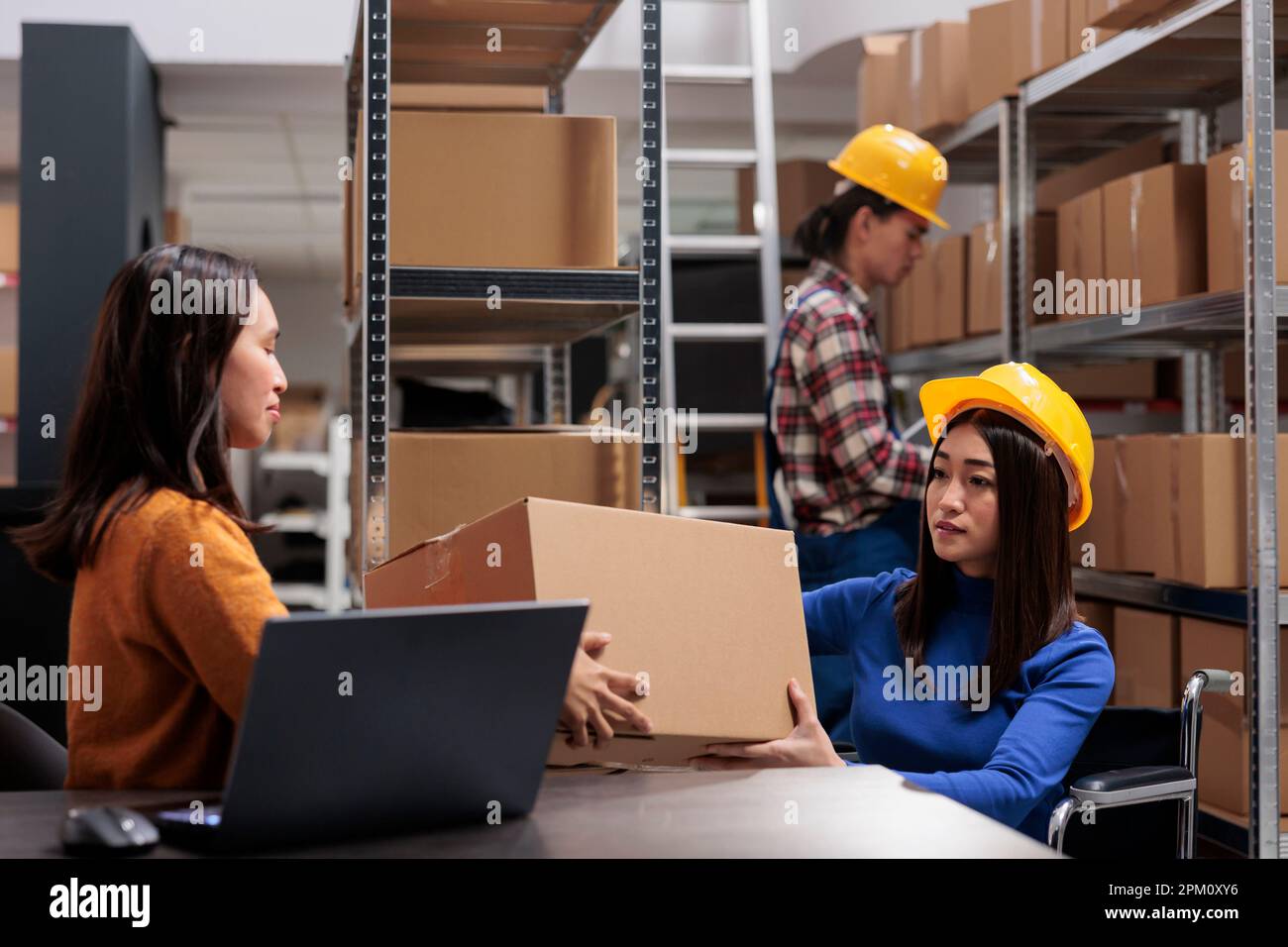 Asian women logistics workers sitting in storehouse, checking inventory ...