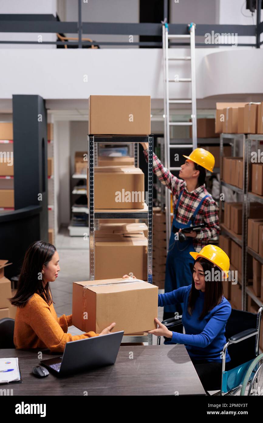 Warehouse order picker giving manager package ready to shipment. Asian ...