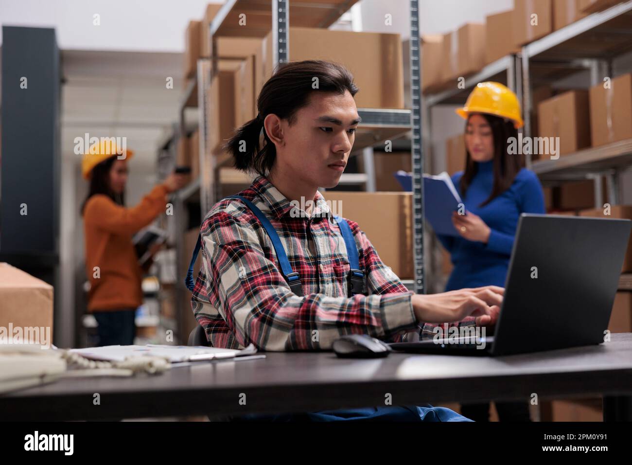 Postal service worker creating parcel invoice on laptop while working ...