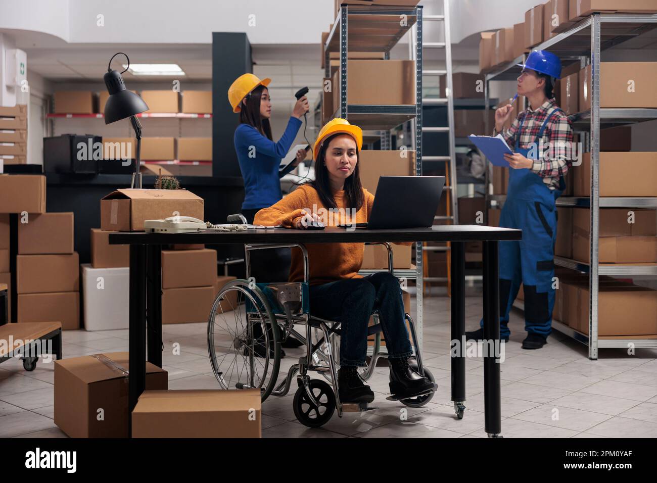 Warehouse employee doing office work in disability friendly workplace. Young asian woman postal ...