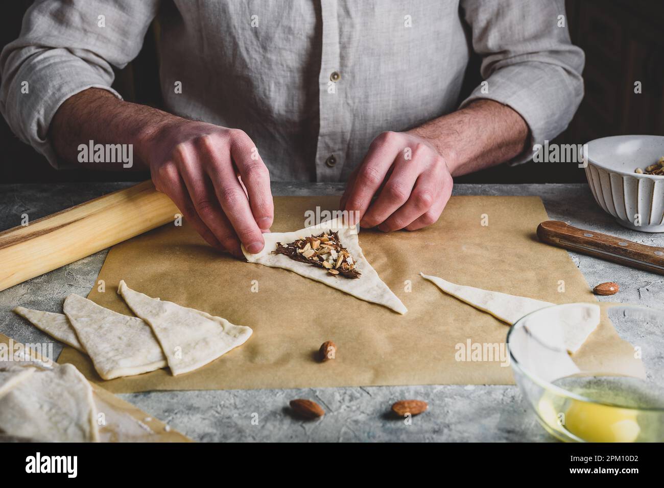 Homemade croissant preparing. Baker rolls the puff pastry stuffed with ...