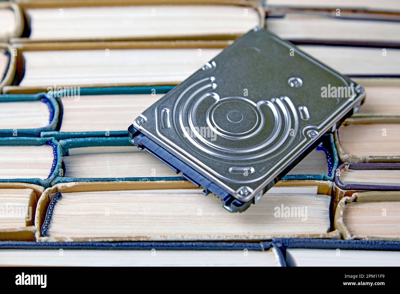 Computer hard drive on the background of a pile of old paper books ...