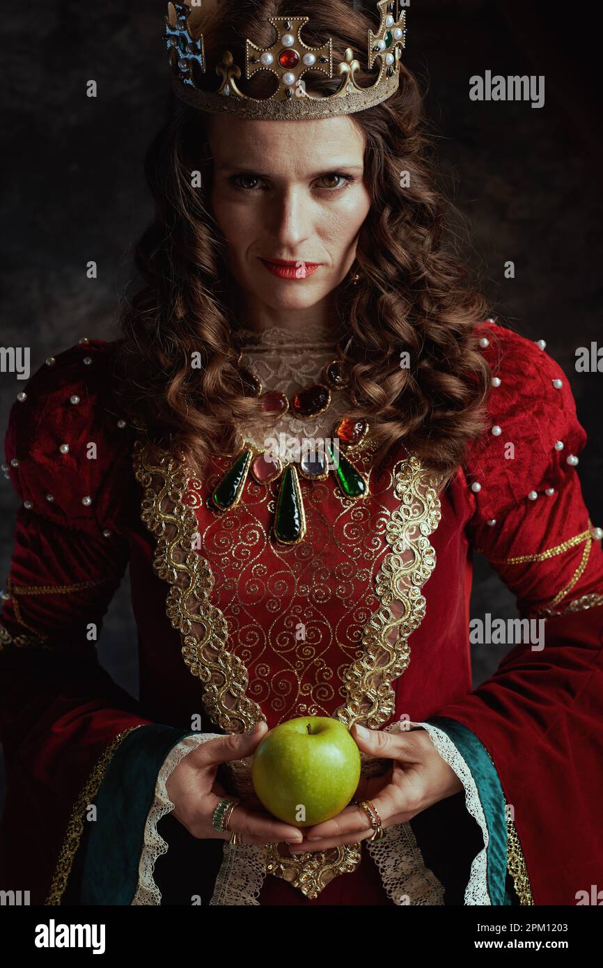 medieval queen in red dress with green apple and crown on dark gray ...