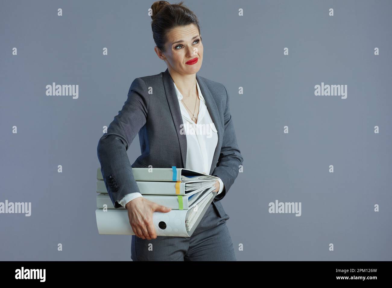 stressed modern 40 years old woman employee in gray suit with folders ...