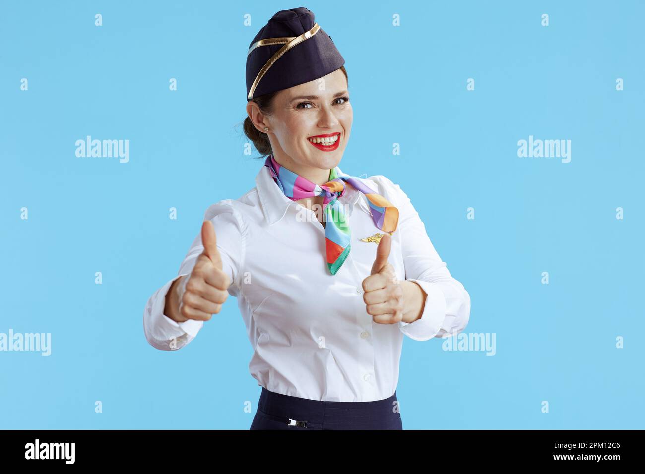 happy stylish air hostess woman on blue background in uniform showing ...