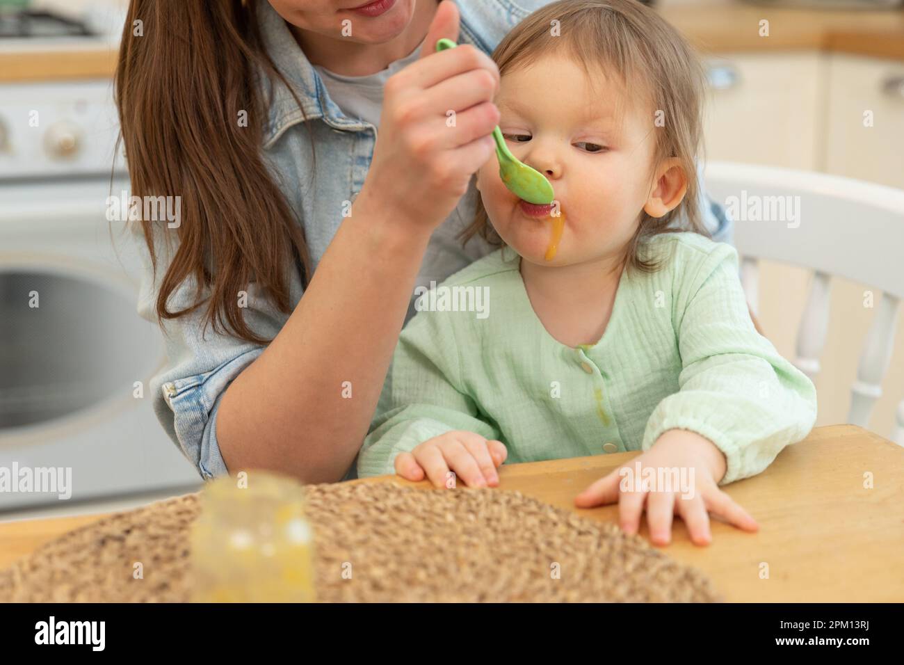 Happy family at home. Mother feeding her baby girl from spoon in ...