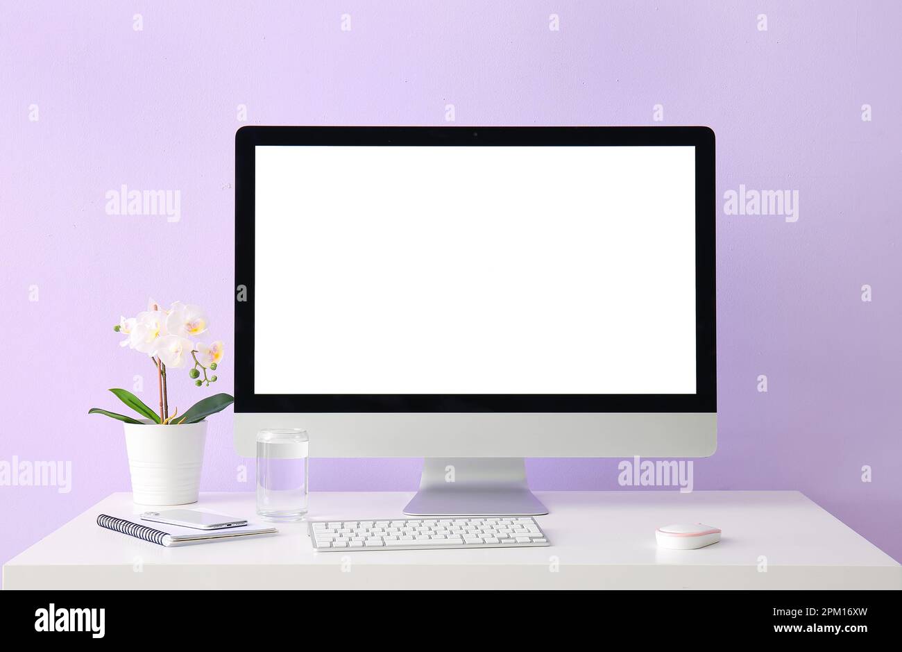 Workplace with computer, mobile phone and flower near lilac wall Stock ...