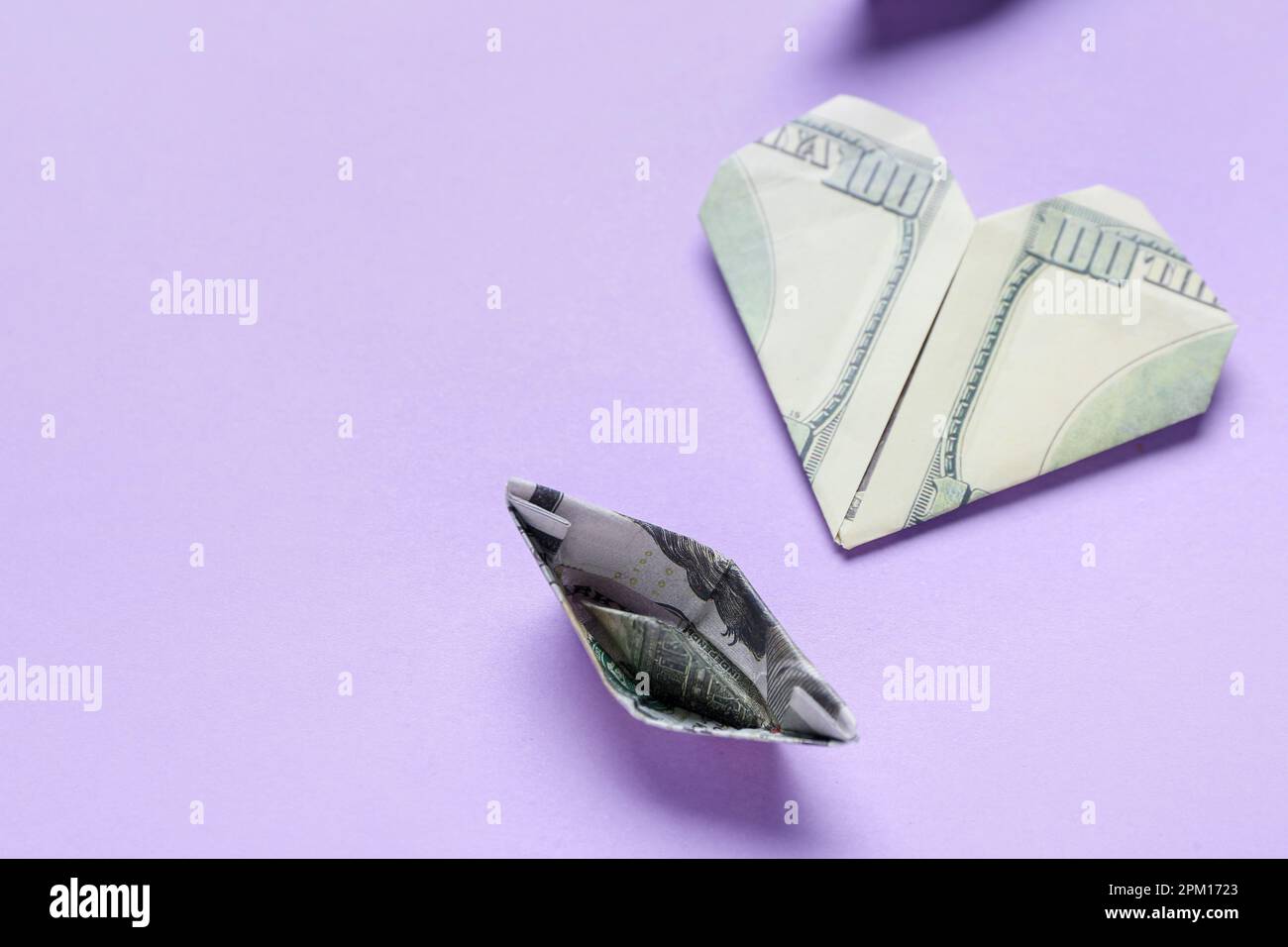 Origami boat and heart made of dollar banknotes on lilac background ...