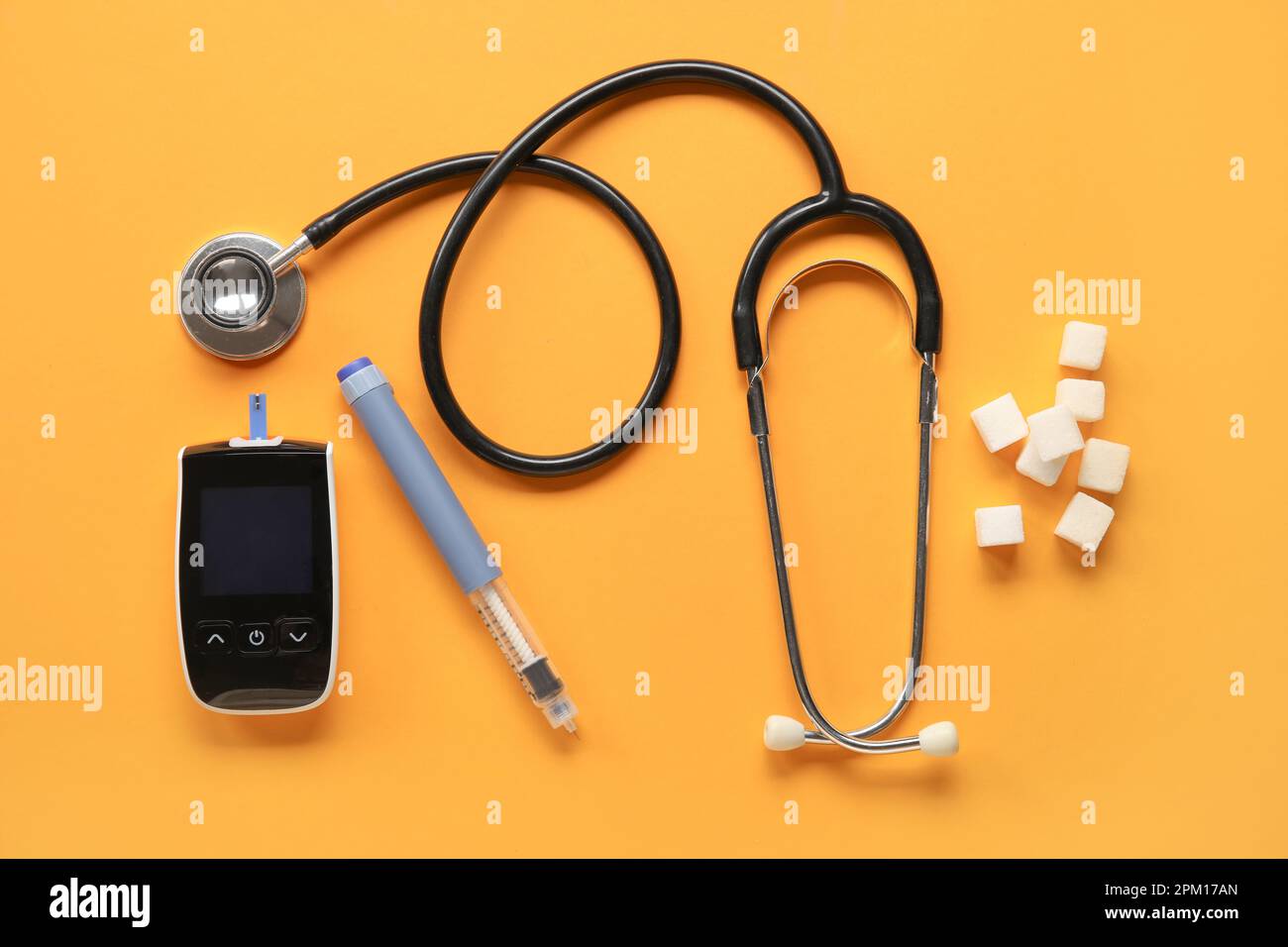 Glucometer with lancet pen, sugar and stethoscope on orange background ...