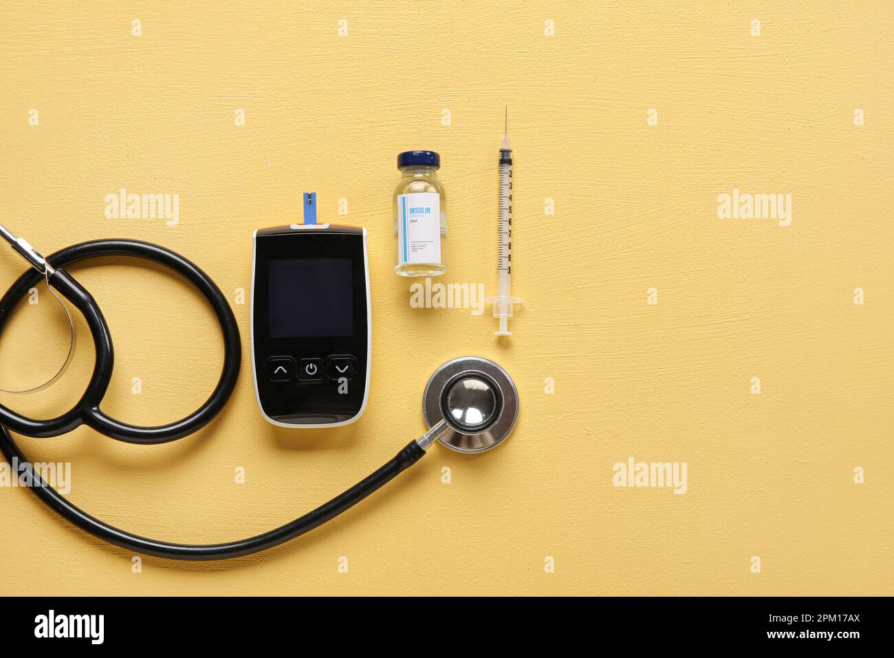 Glucometer with insulin, syringe and stethoscope on yellow background ...