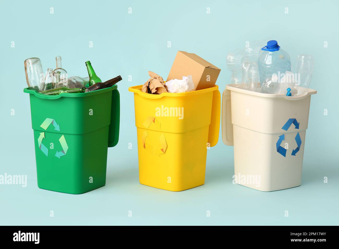 Containers with different types of garbage on light blue background ...