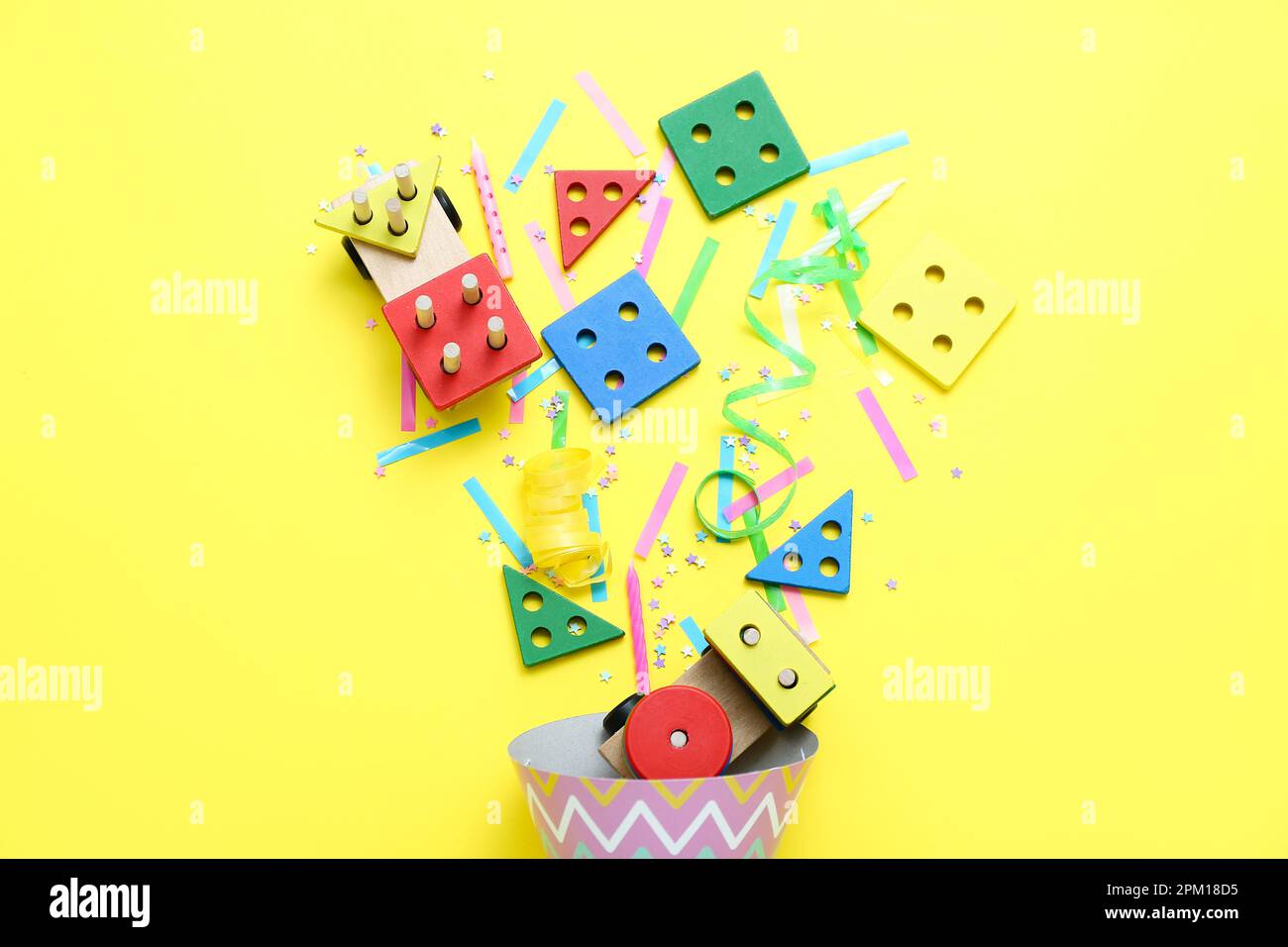 Party cone with baby blocks and confetti on yellow background. Children ...