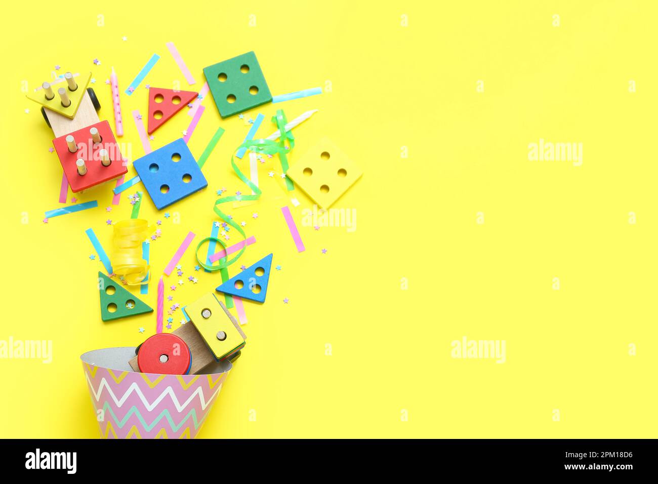 Party cone with baby blocks and confetti on yellow background. Children ...