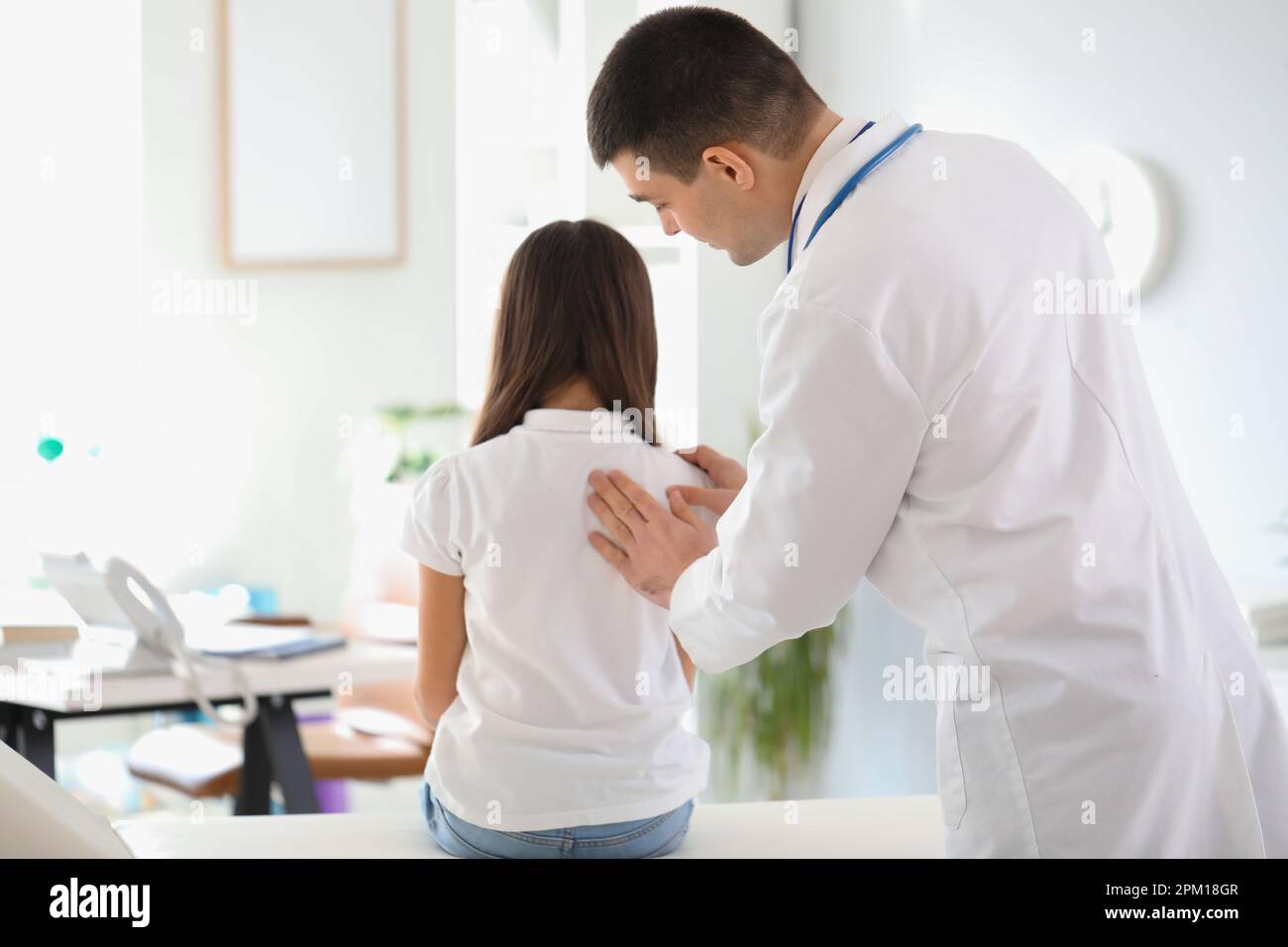 Doctor checking posture of little girl in clinic Stock Photo - Alamy