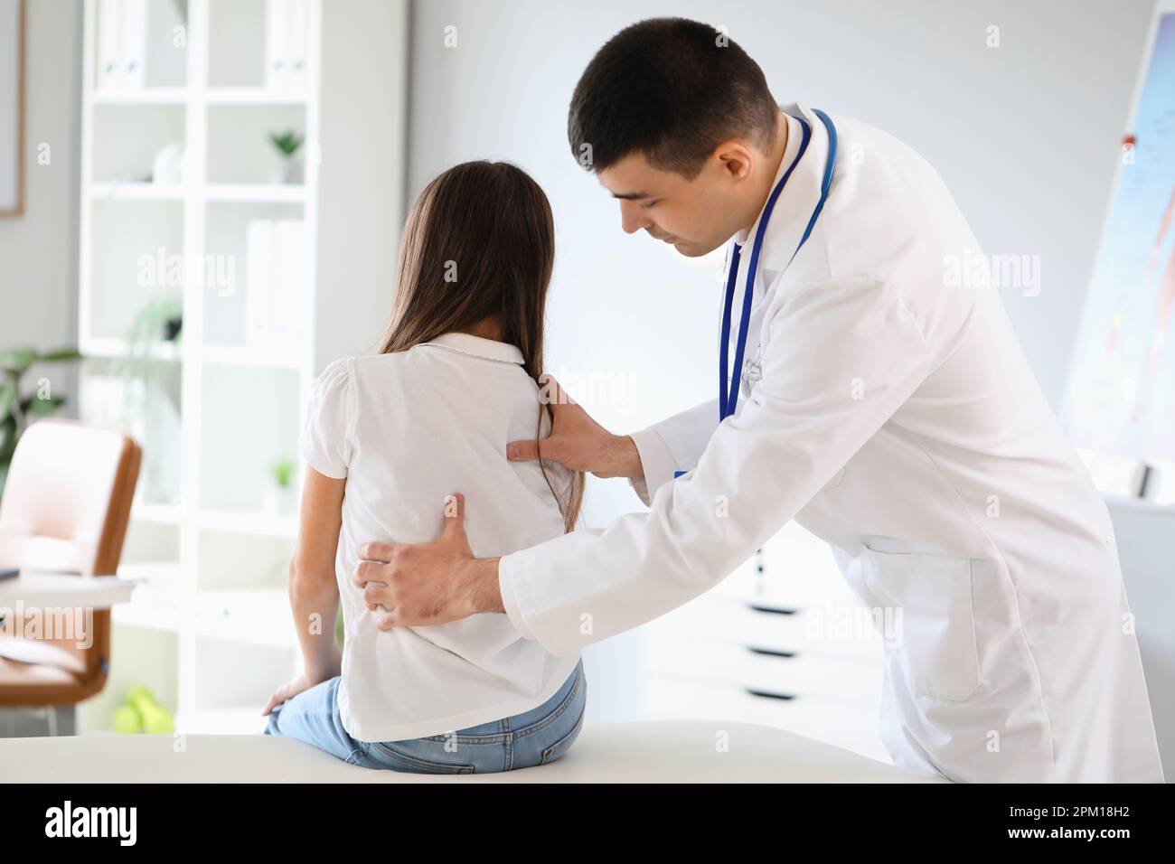 Doctor checking posture of little girl in clinic Stock Photo - Alamy