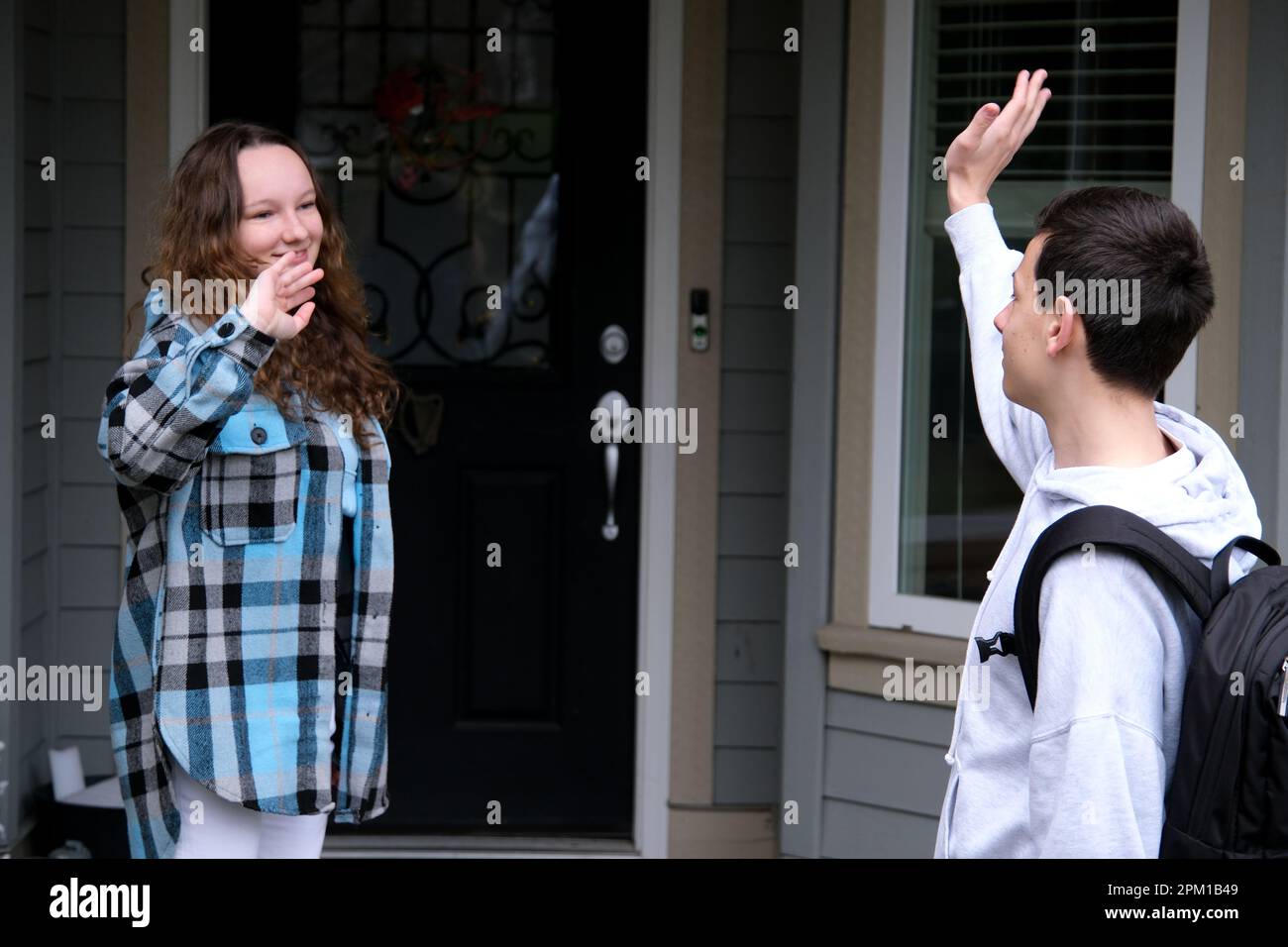 Young people, man and woman greeting or saying goodbye by waving hands ...