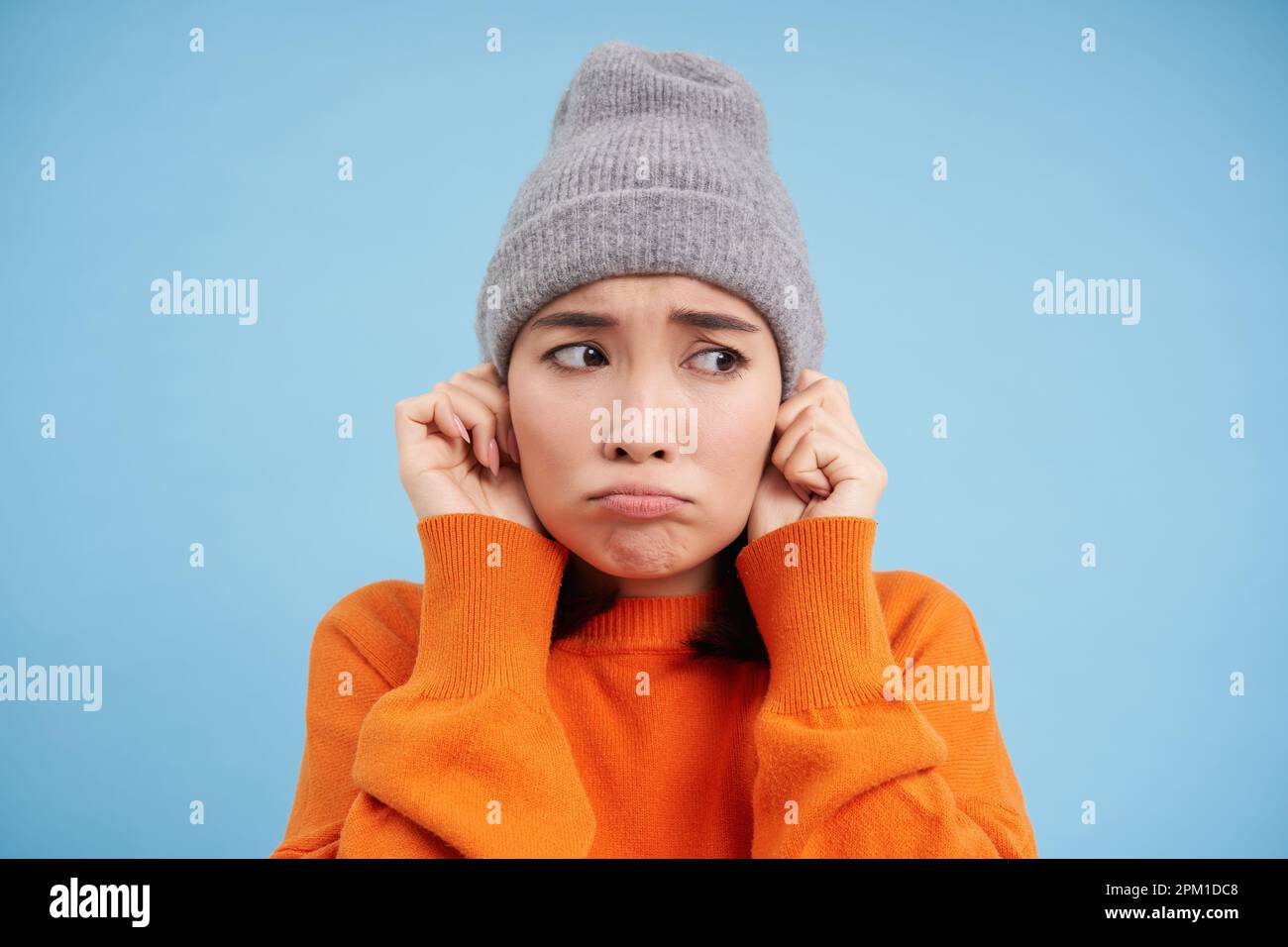 Close up portrait of korean girl feels cold, shakes and freezes, puts ...