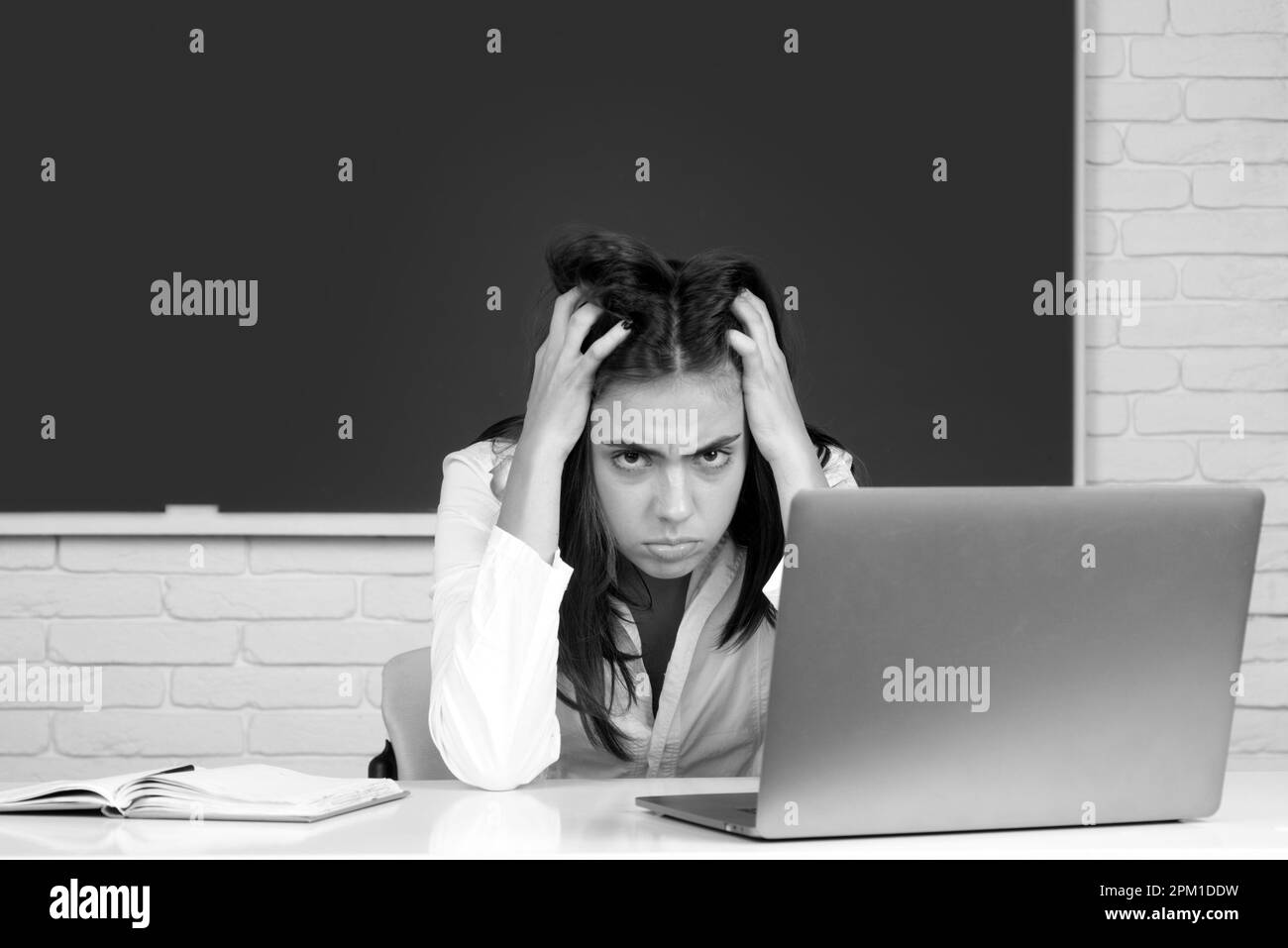 Sad and angry student using computer in classroom Stock Photo - Alamy
