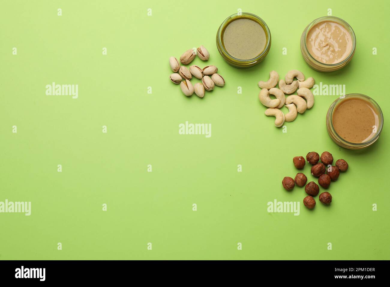 Different types of delicious nut butters and ingredients on light green ...