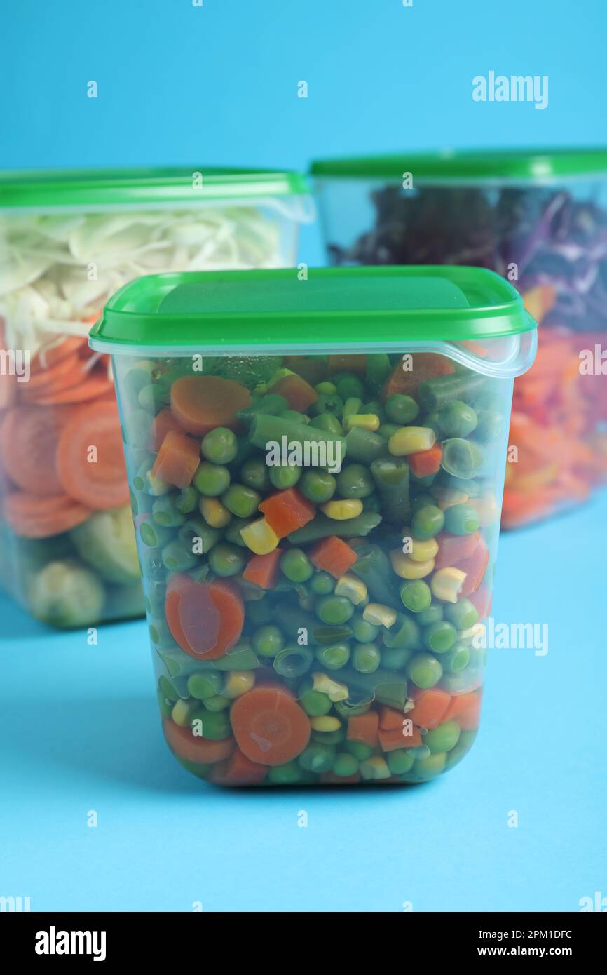 Set of plastic containers with fresh food on light blue background ...