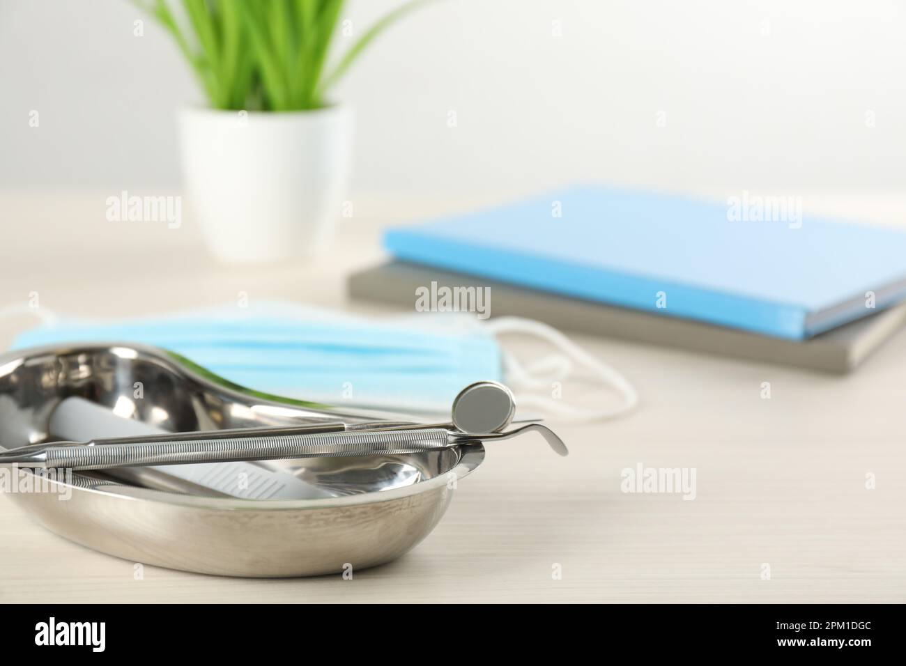 Kidney shaped tray with set of dentist's tools on wooden table, closeup ...